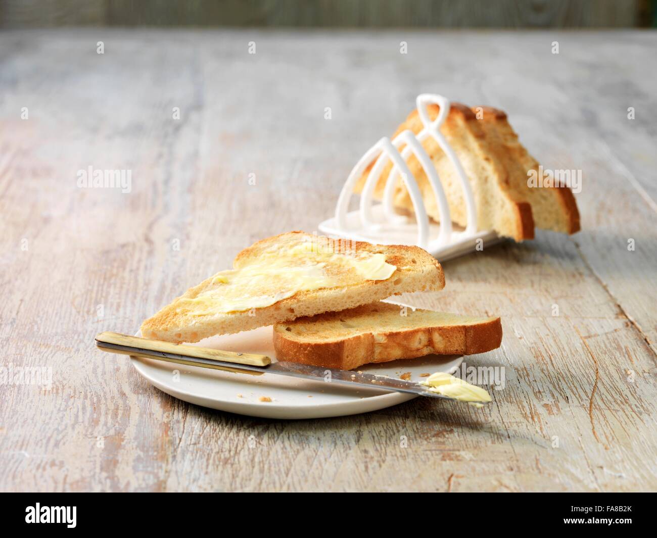 Butter melting on sliced white bread on plate and toast rack Stock ...