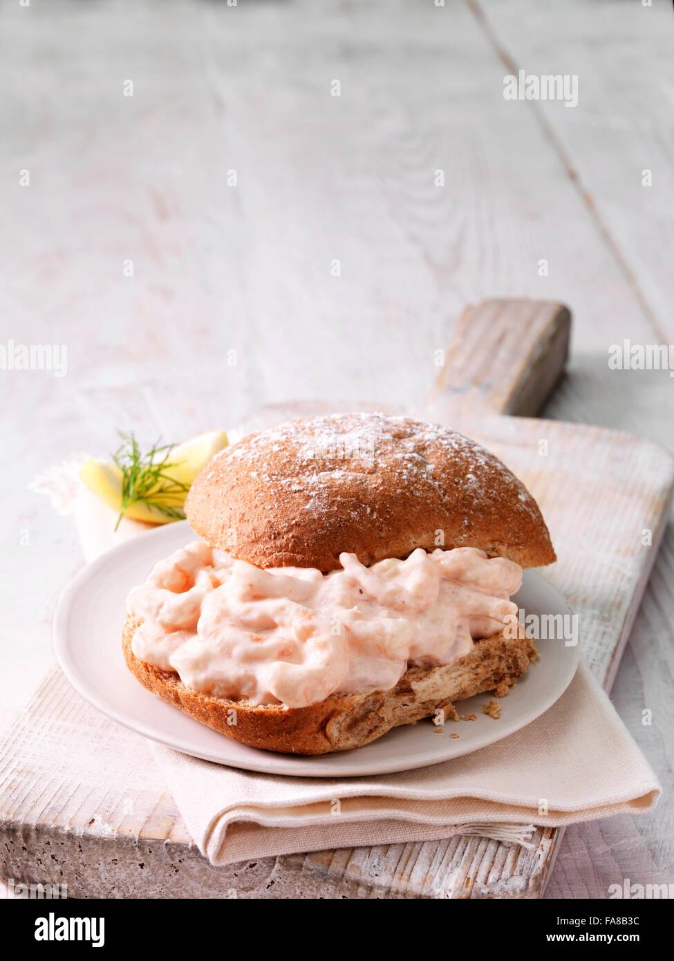 Prawn cocktail sandwich in wholemeal bun with lemon wedge garnished ...