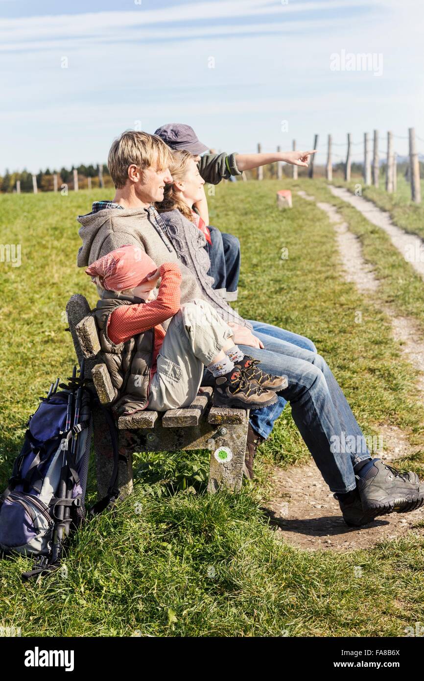 Side view of family sitting on park bench looking out at view Stock ...