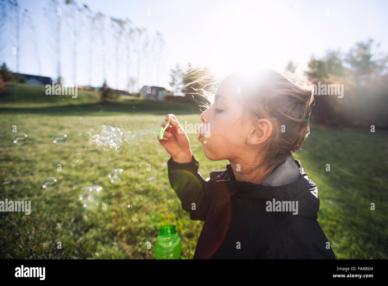 Head and shoulders side view of girl looking down blowing bubbles Stock ...