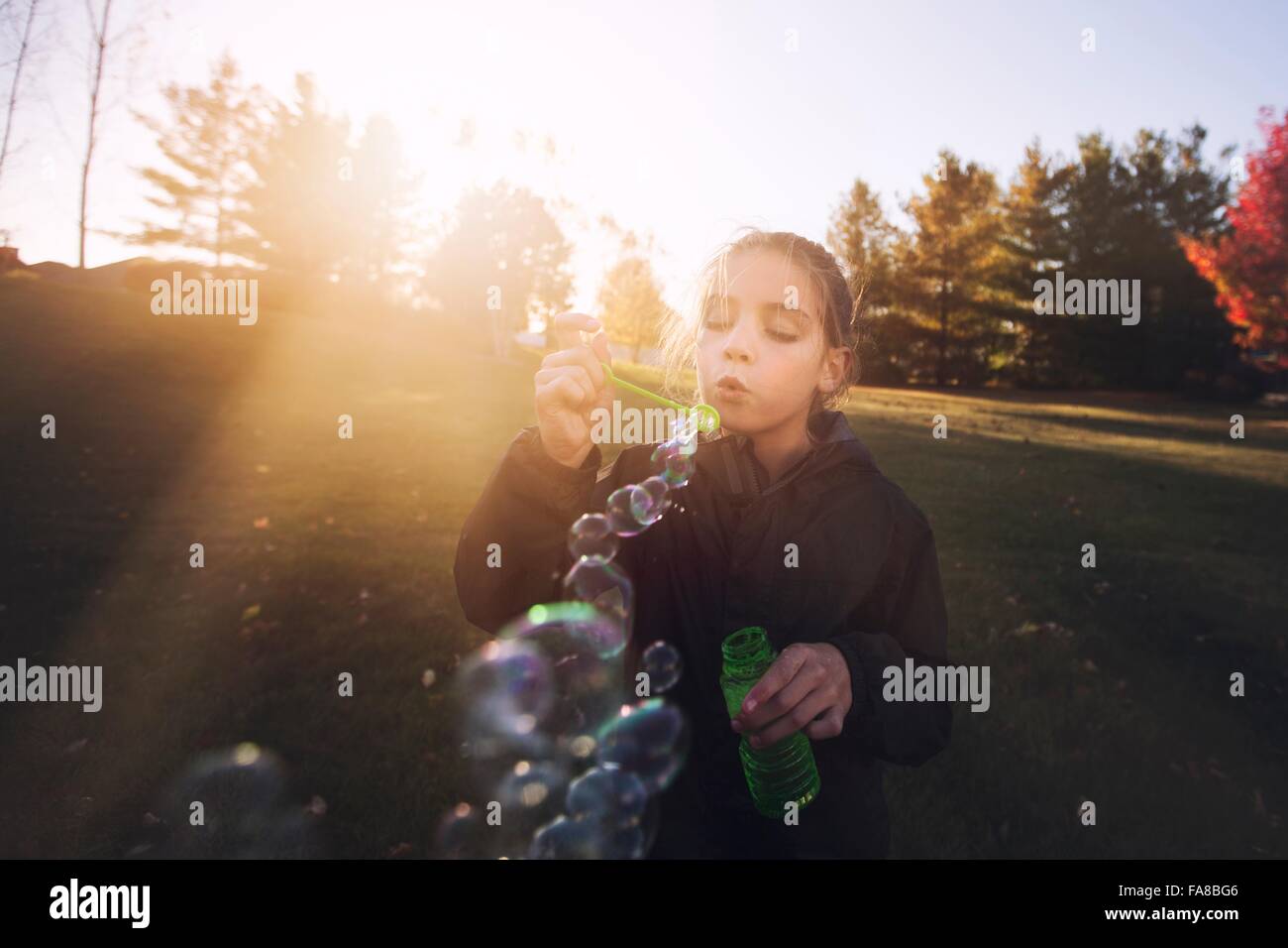 Waist up front view of girl looking down blowing bubbles Stock Photo ...