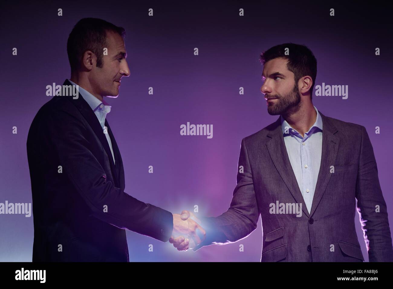 Two men shaking hands, light illuminating handshake Stock Photo - Alamy