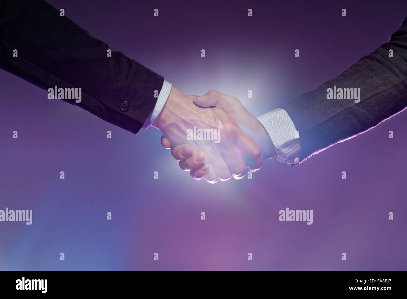 Two men shaking hands, light illuminating handshake, close-up Stock ...
