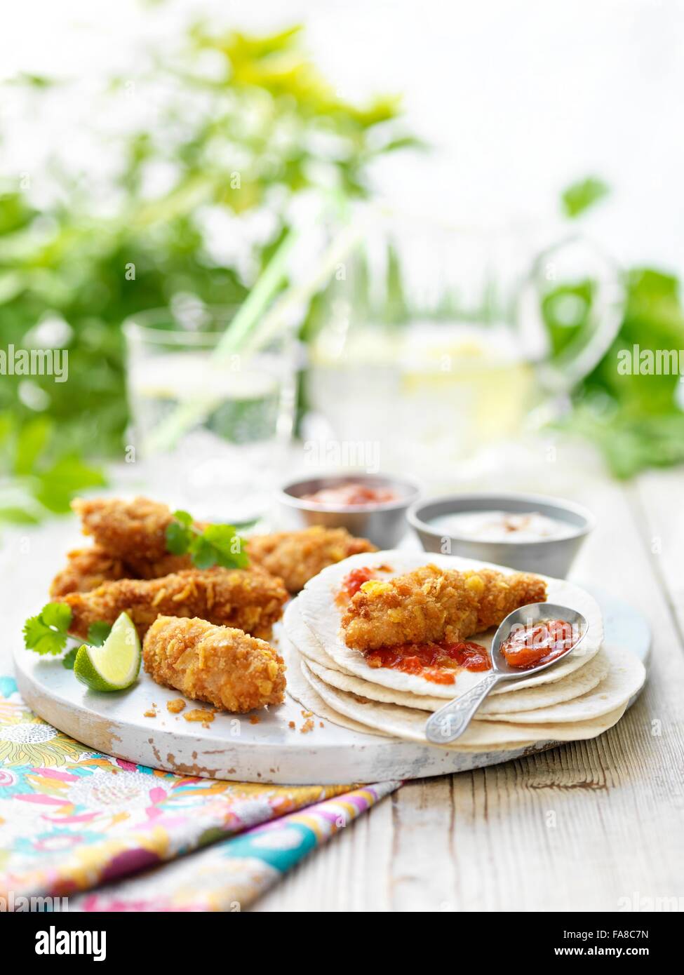 Mini crispy chicken fajitas with tortilla wraps, lime slice, tomato ...
