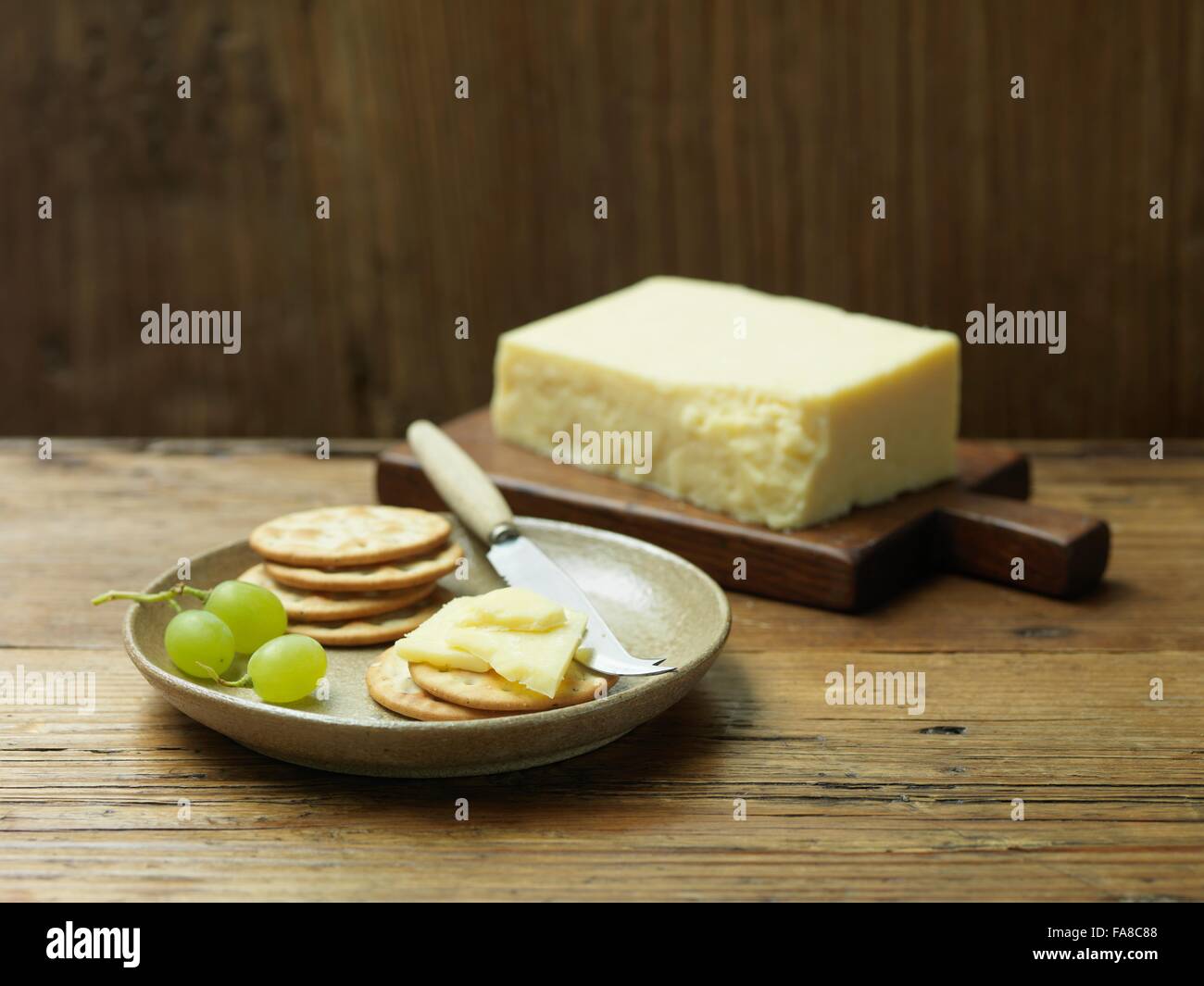 Mature cheddar cheese with water biscuits and grapes on wood Stock ...