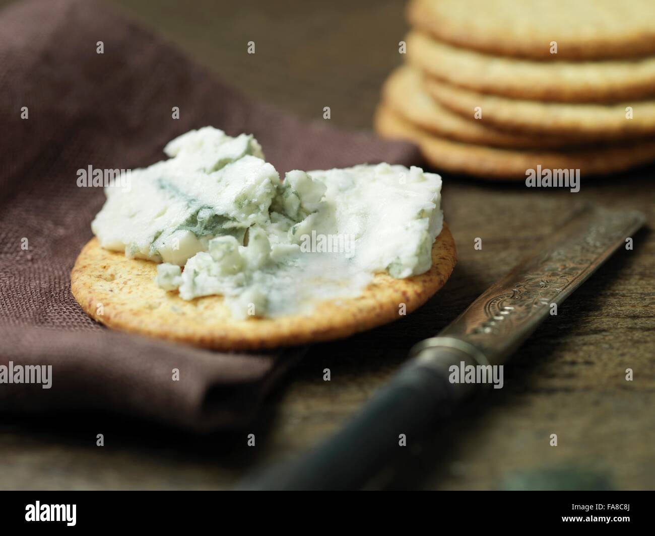 Beacon blue cheese on cracker with vintage knife and tea towel on ...