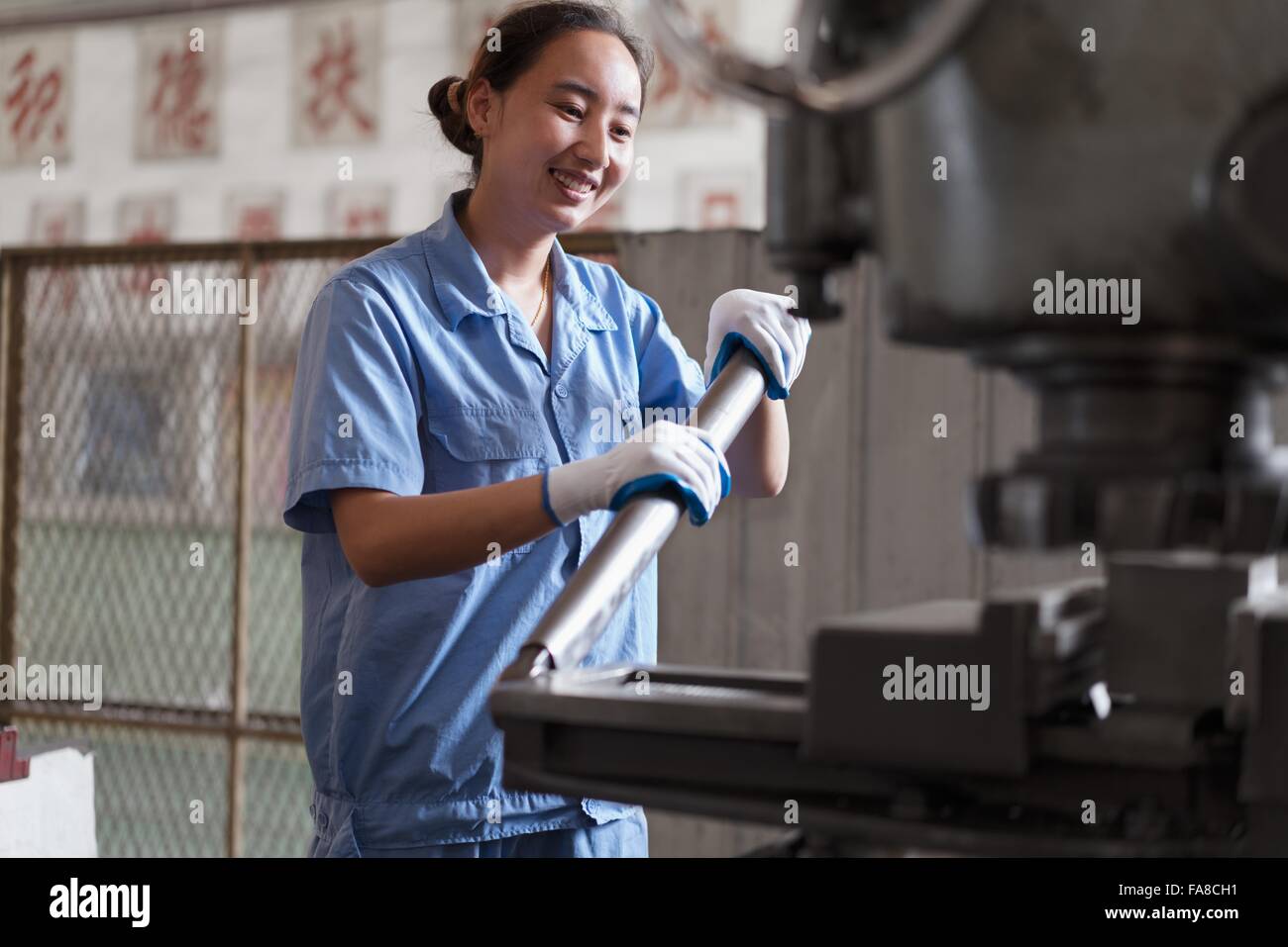 Female factory worker pushing machine lever in crane factory, China ...