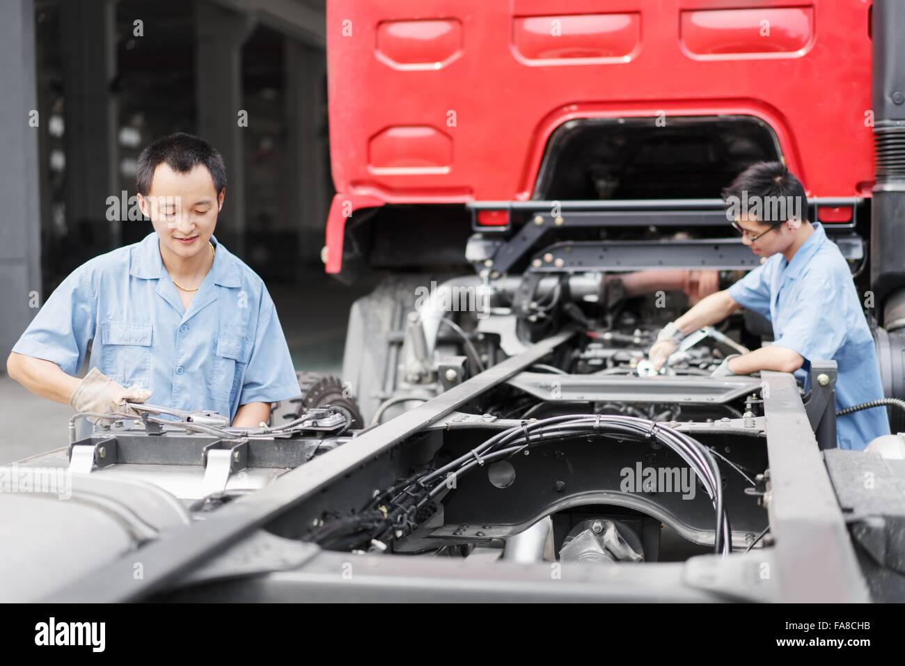 Two male factory workers teamworking on truck at crane factory, China ...