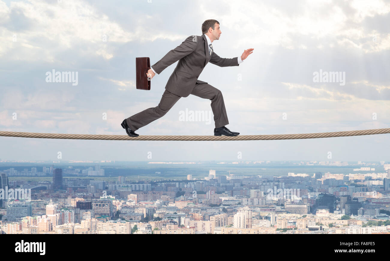 Businessman running on rope Stock Photo - Alamy