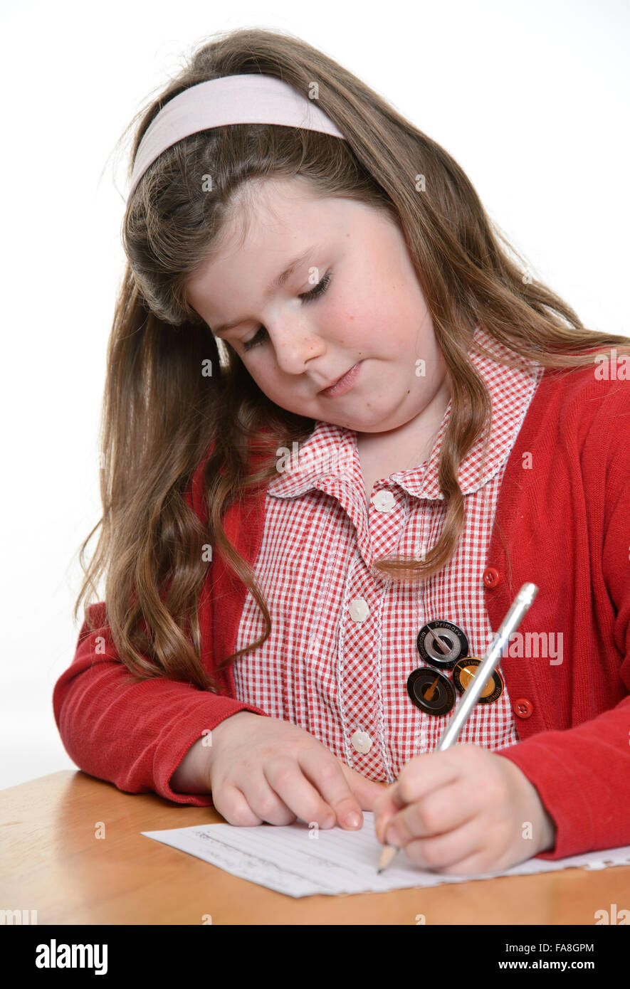 A school girl (Primary School age) studying, reading and writing and ...