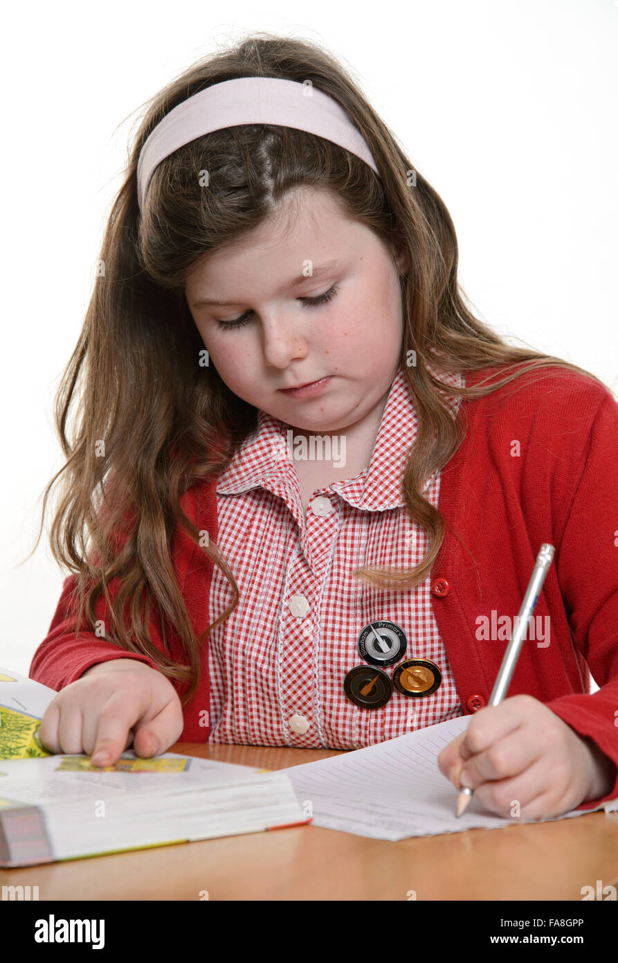 A school girl (Primary School age) studying, reading and writing and ...