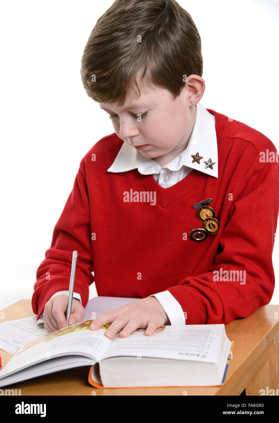 A young (primary school age) boy in a red school uniform sweater ...