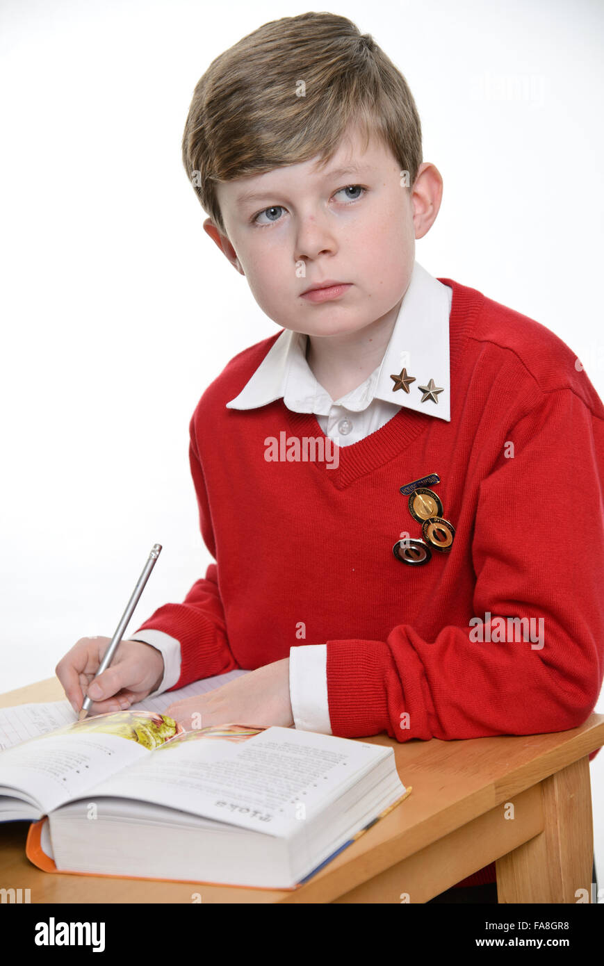 A young (primary school age) boy in a red school uniform sweater ...