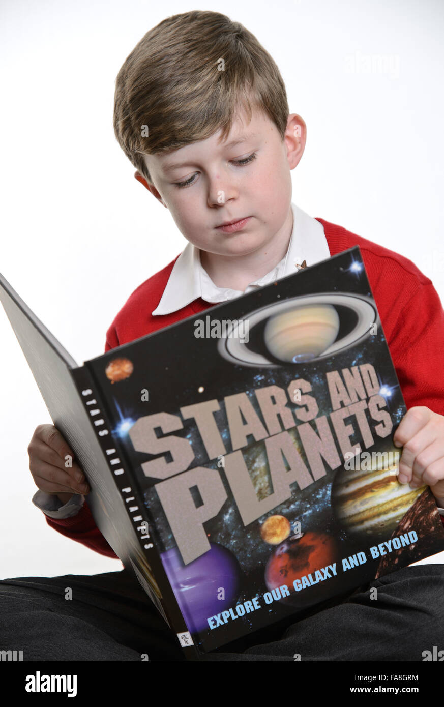 A young (primary school age) boy in a red school uniform sweater ...