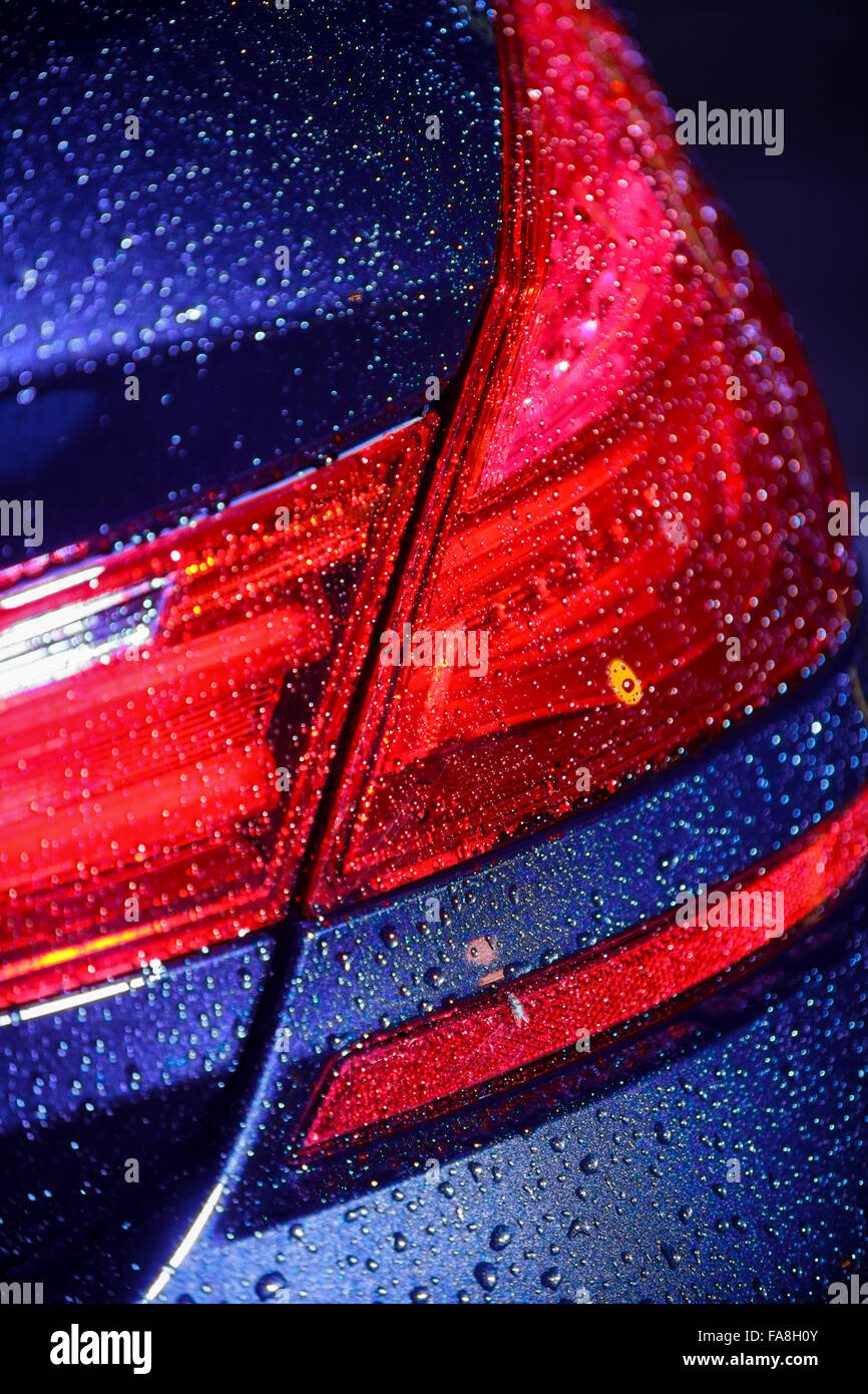 Color image with a car's rear brake light, covered with rain drops ...