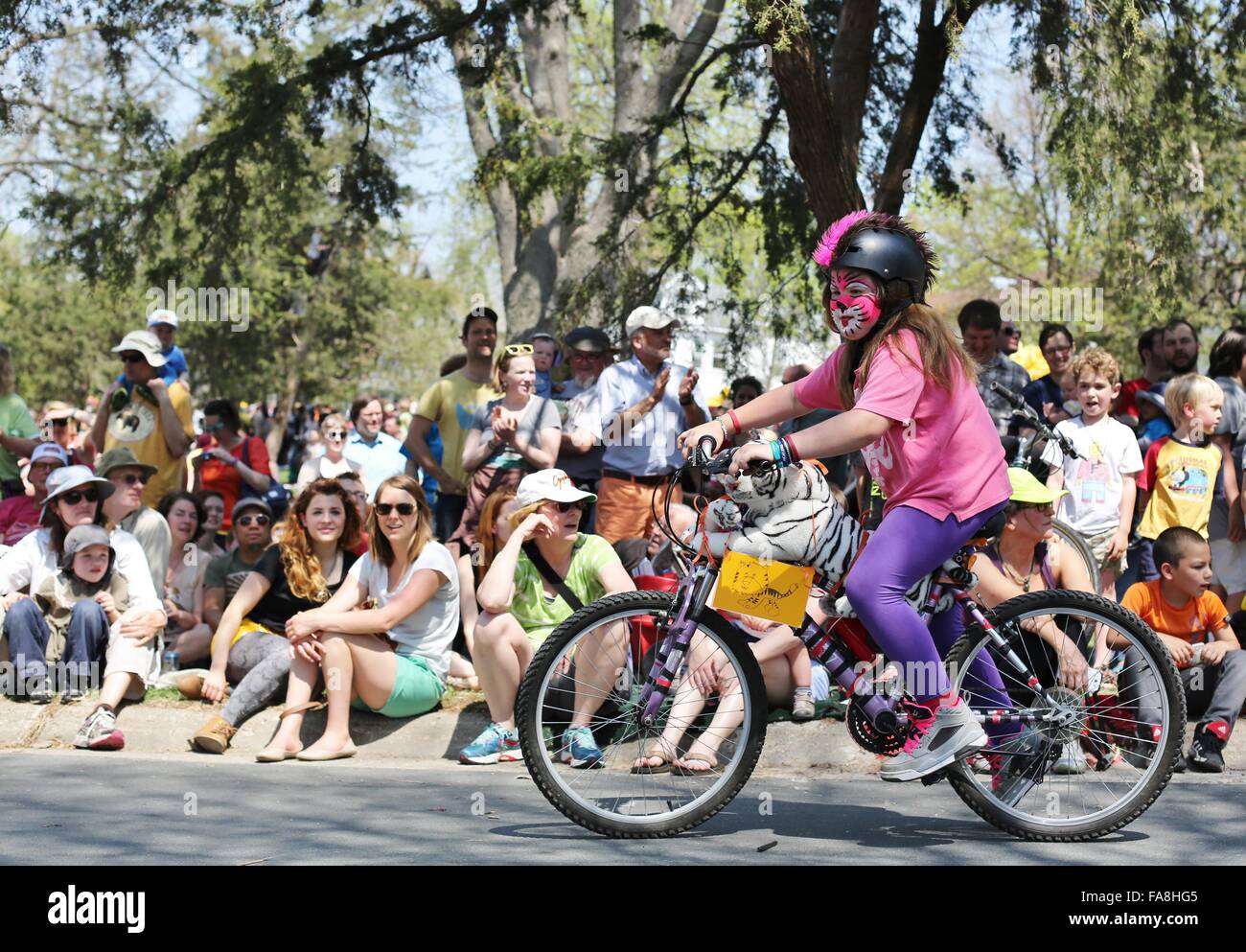 A young girl riding a bicycle and wearing a costume in the May Day ...