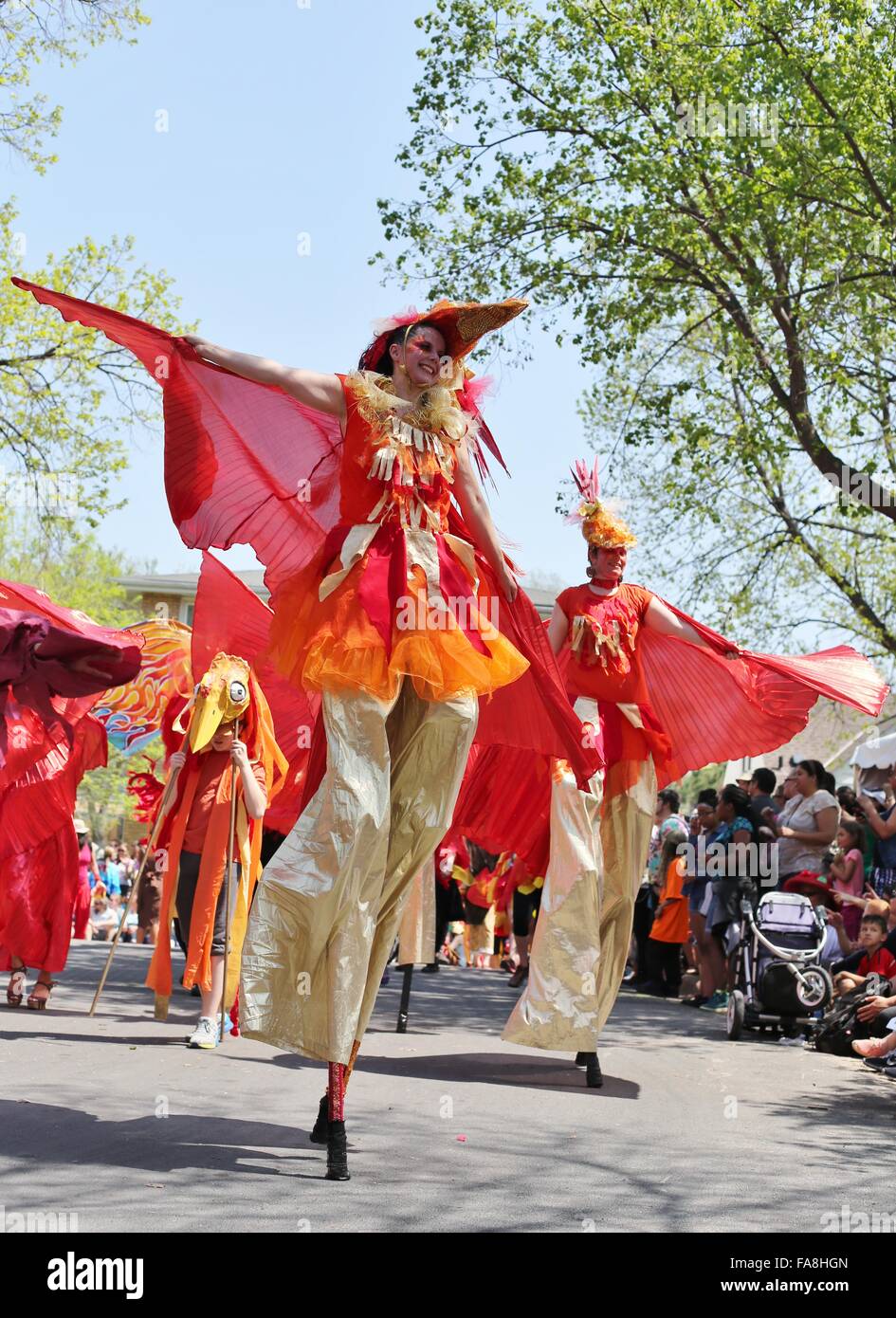 People in colorful costumes and on tall stilts at the May Day parade in ...