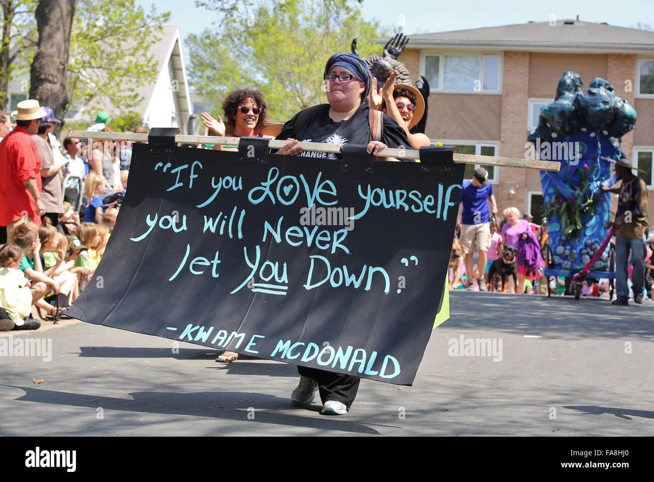 A woman carrying a sign about self love in the May Day parade in ...