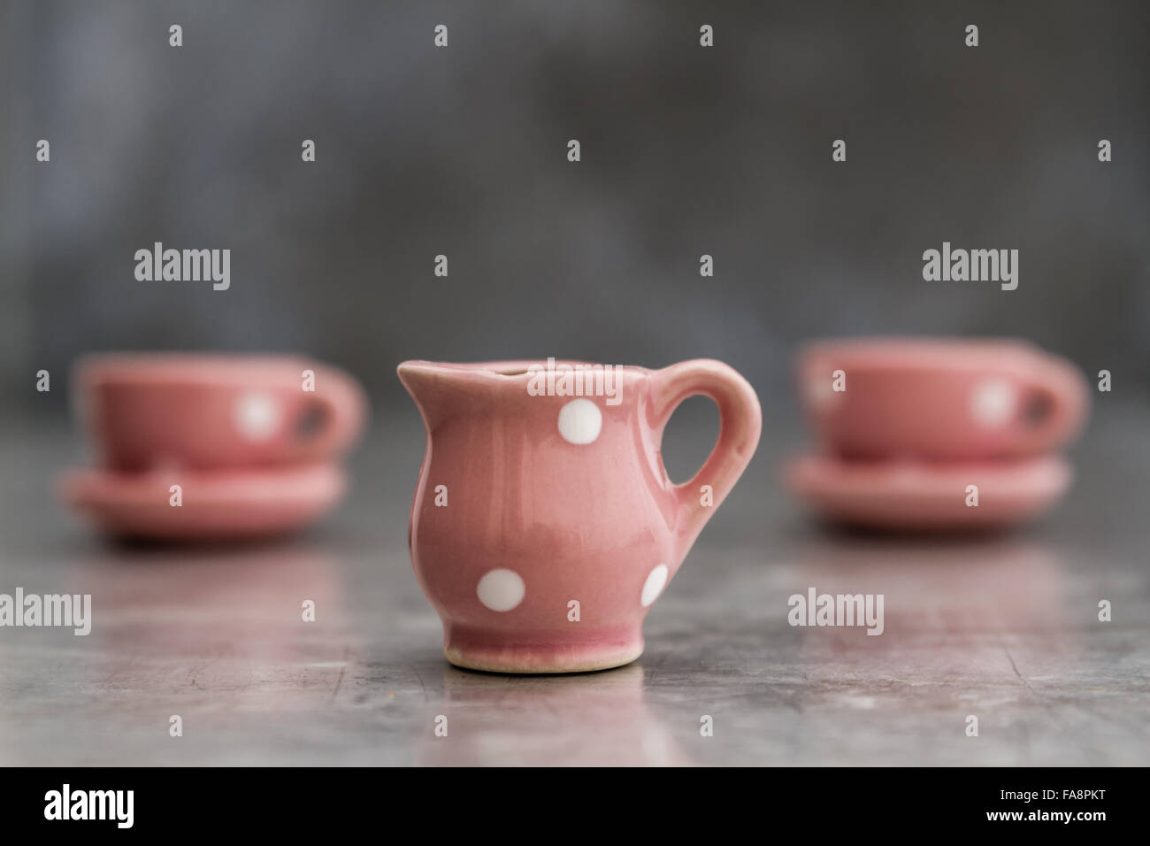 Little pink toy porcelain cups and plates with white dots on gray ...