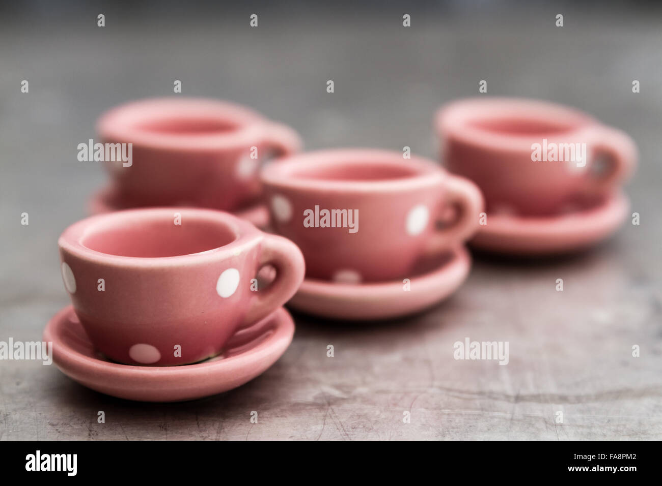Little pink toy porcelain cups and plates with white dots on gray ...