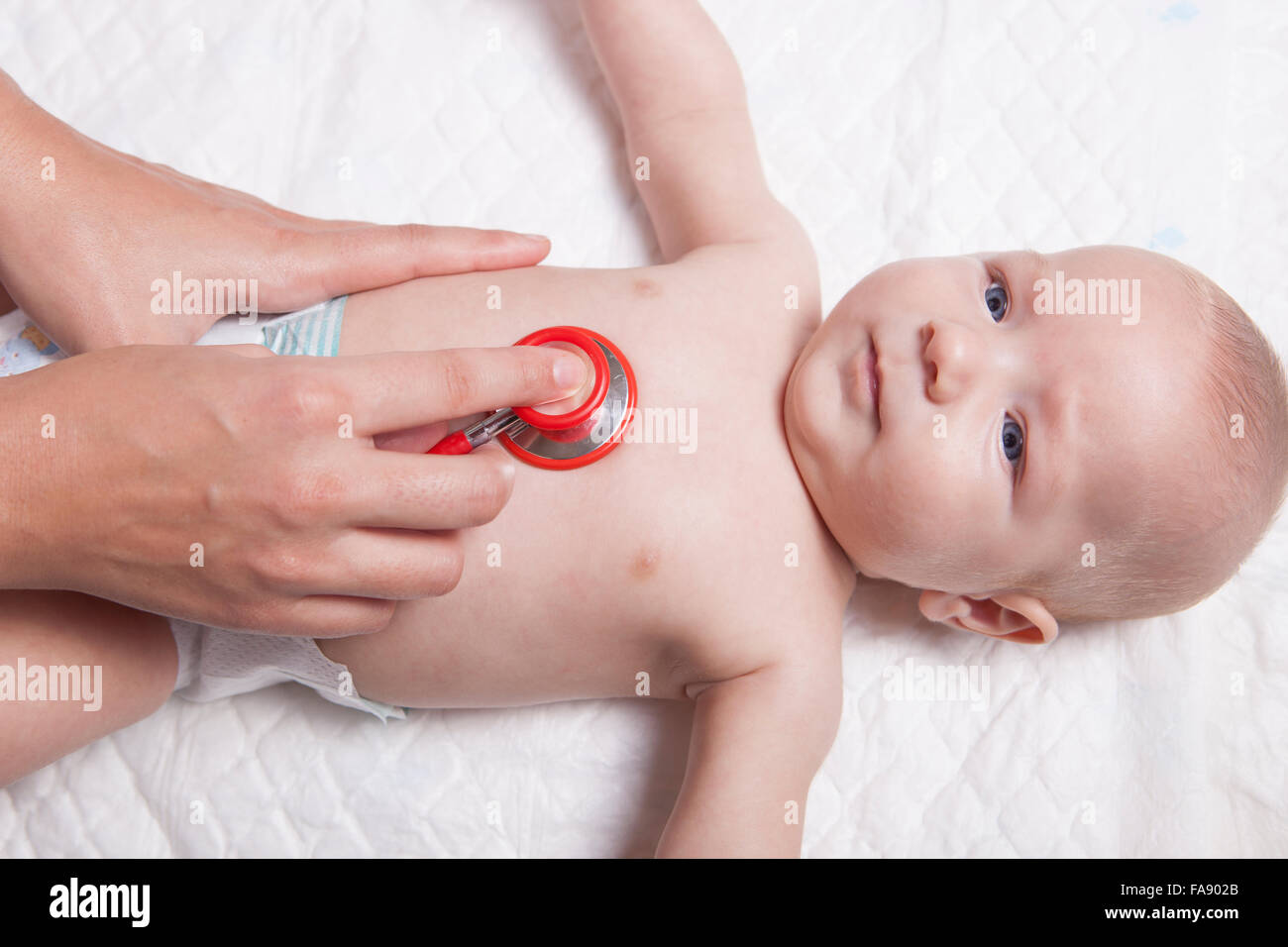 Pediatrician in white lab coat examines three months baby boy using a ...