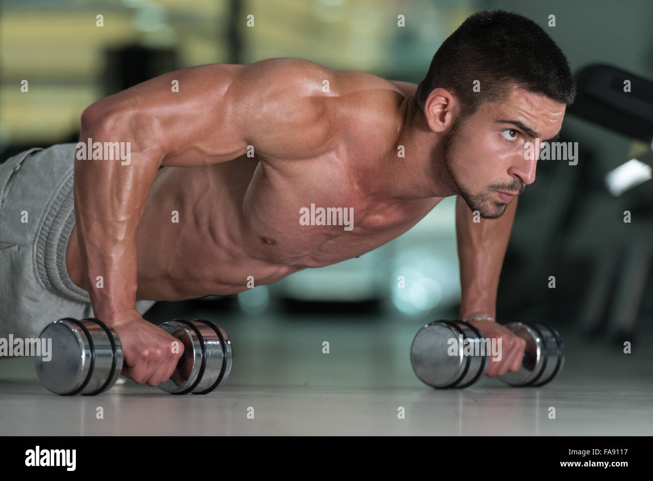 Young Athlete Doing Pushups With Dumbbells As Part Of Bodybuilding ...
