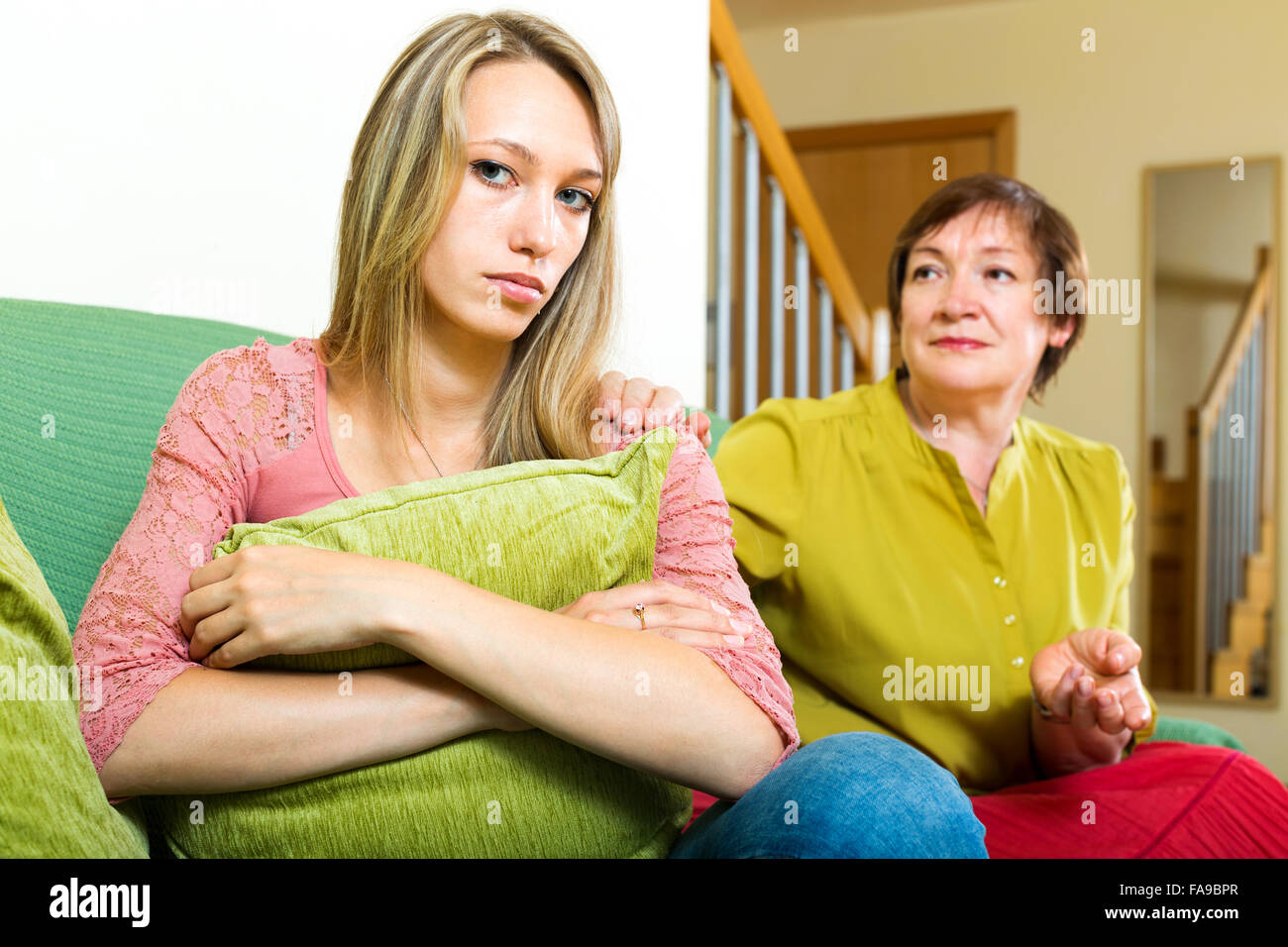 Worried mother talking to a sad daughter on the couch in the room Stock ...