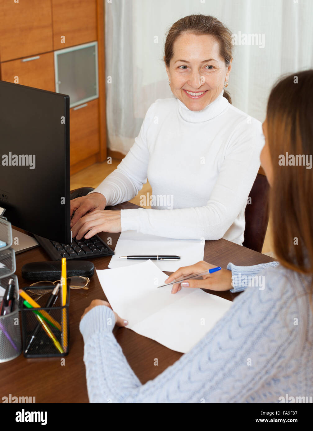 Young woman answer questions of employee at office Stock Photo - Alamy
