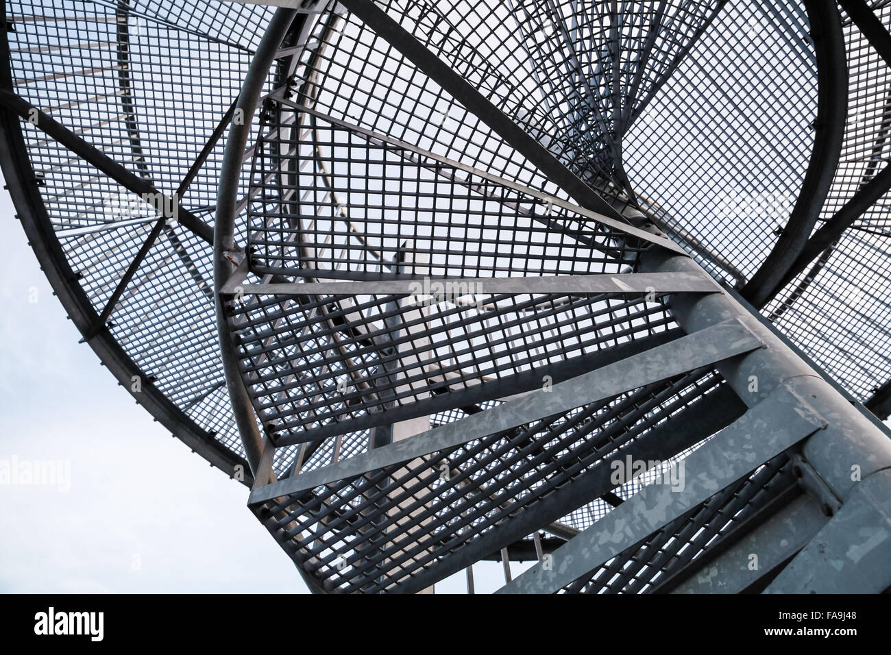 Metal spiral ladder, black silhouette over bright blue sky, photo with ...