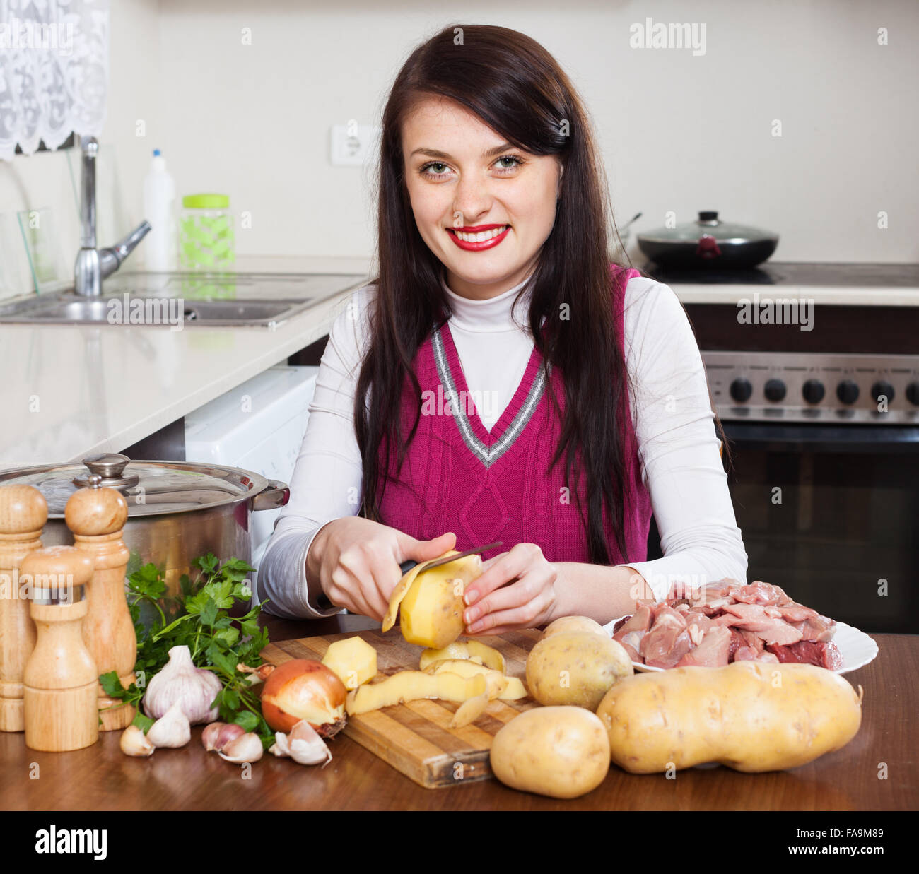 Brunette woman cooking potatoes with meat in kitchen Stock Photo - Alamy