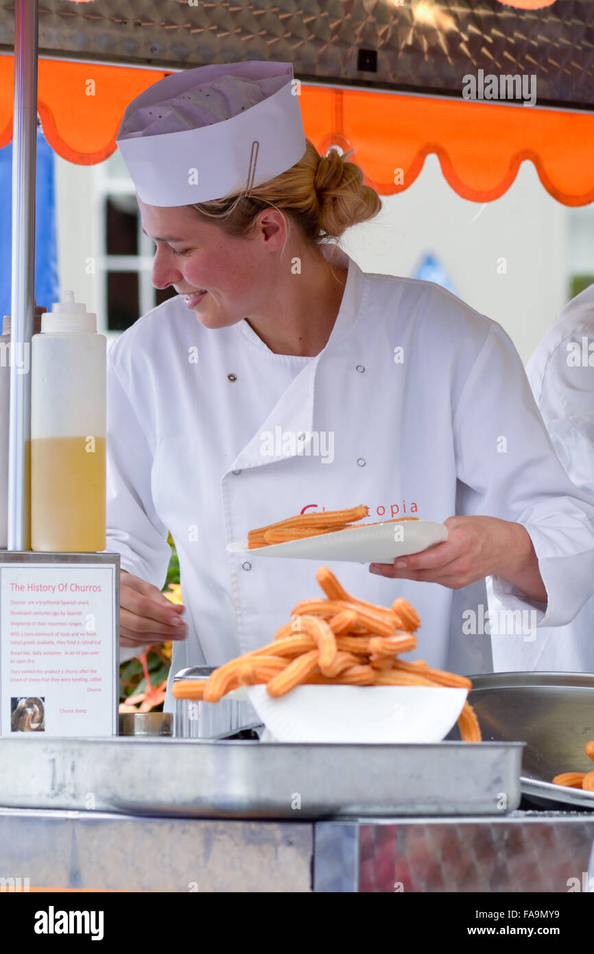 Woman preparing order of churros at stall during Food Festival in ...
