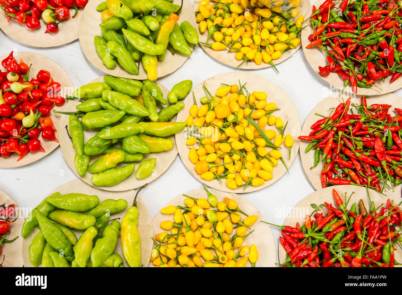 Colorful hot peppers in bright red, yellow, and green piles at farmers ...