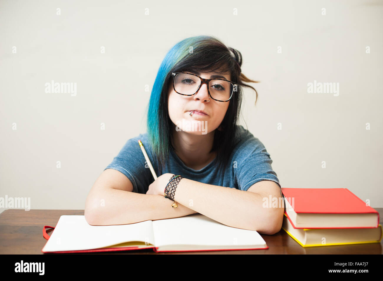 Young bored female teen student with red book on desktop looking at ...