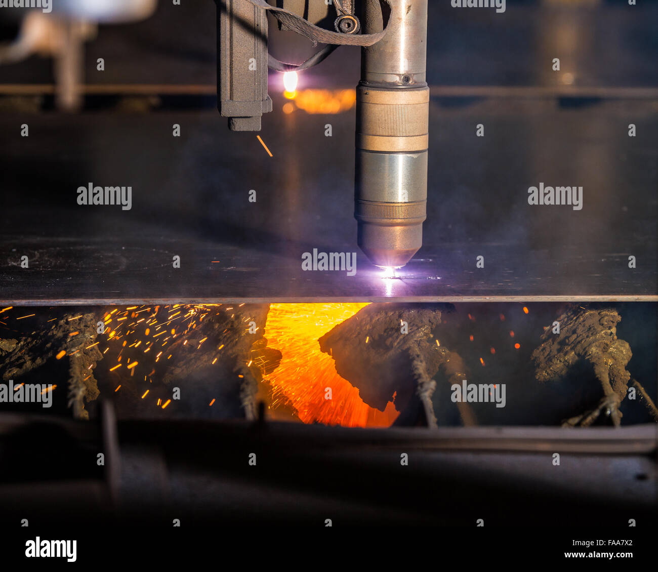 Steel plate being cut by CNC plasma torch with red sparks shooting out ...
