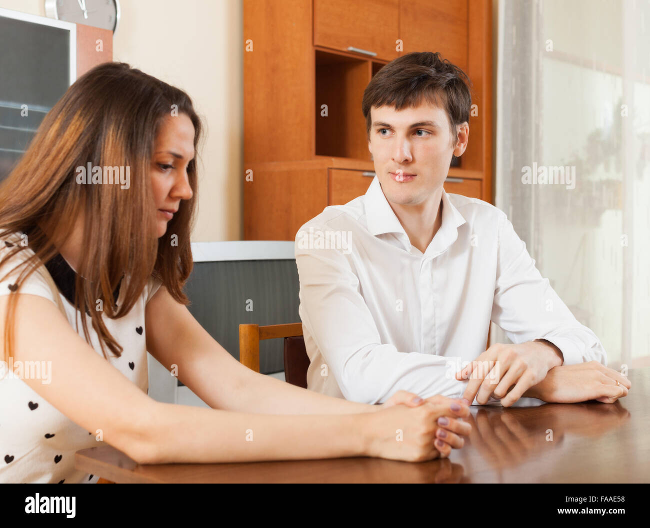 Serious young couple talking in home interior Stock Photo - Alamy