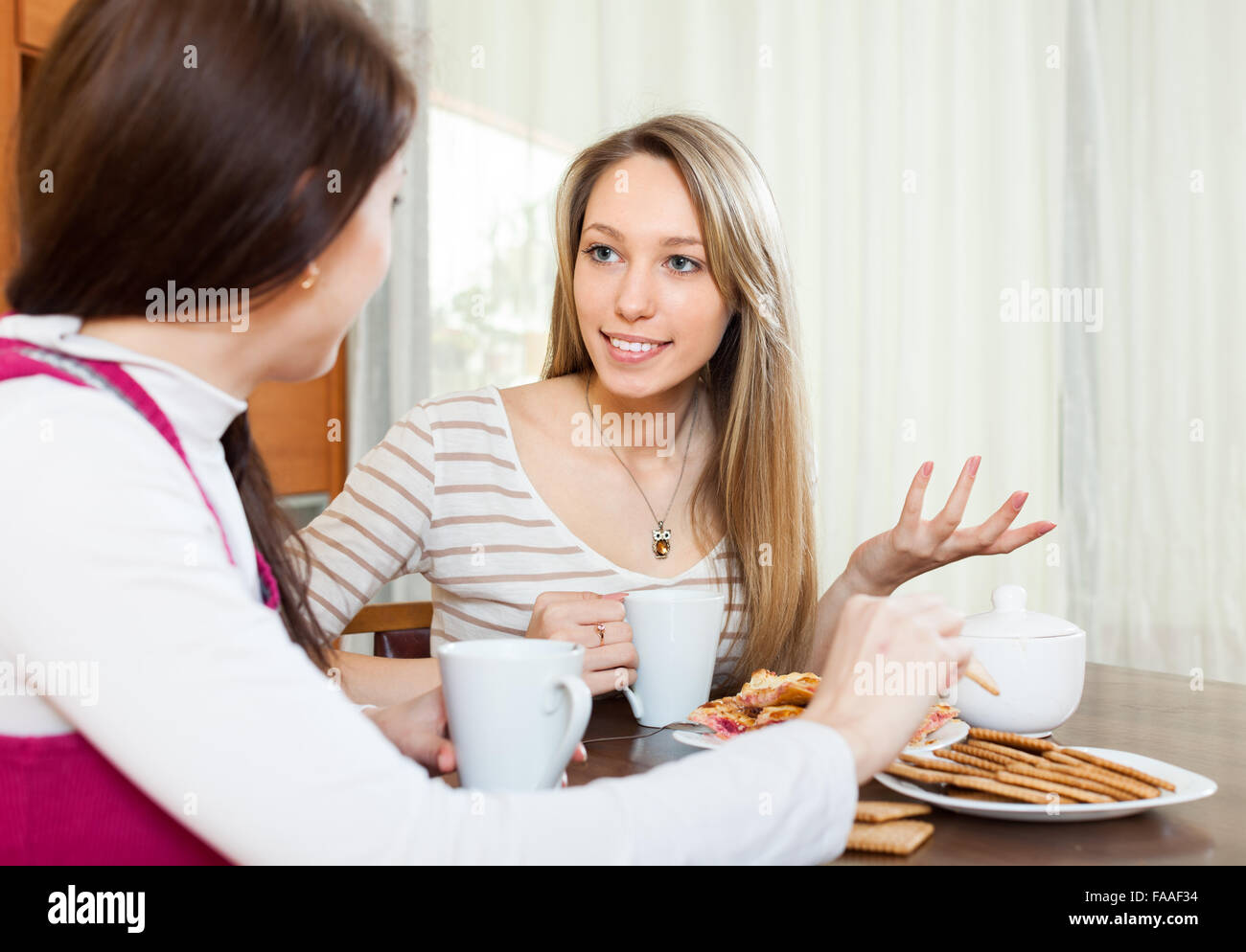 two happy girls drinking tea and gossiping Stock Photo - Alamy