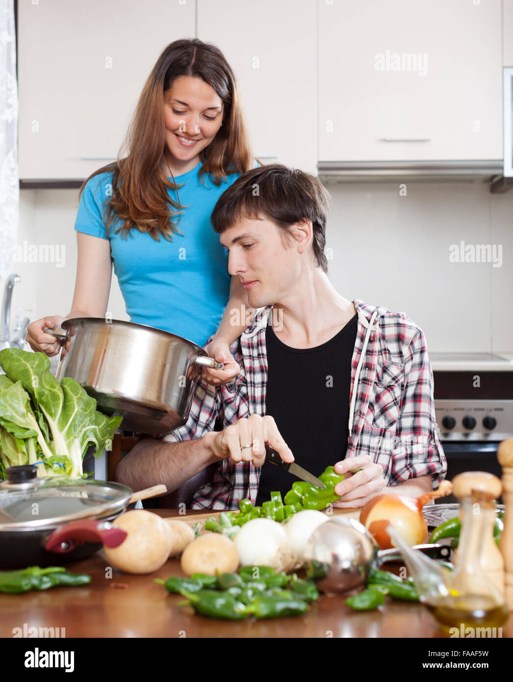 Young man and woman cooking with vegetables in kitchen Stock Photo - Alamy
