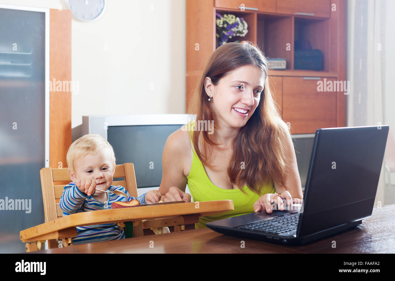 Happy young mother working with laptop and baby in home Stock Photo - Alamy