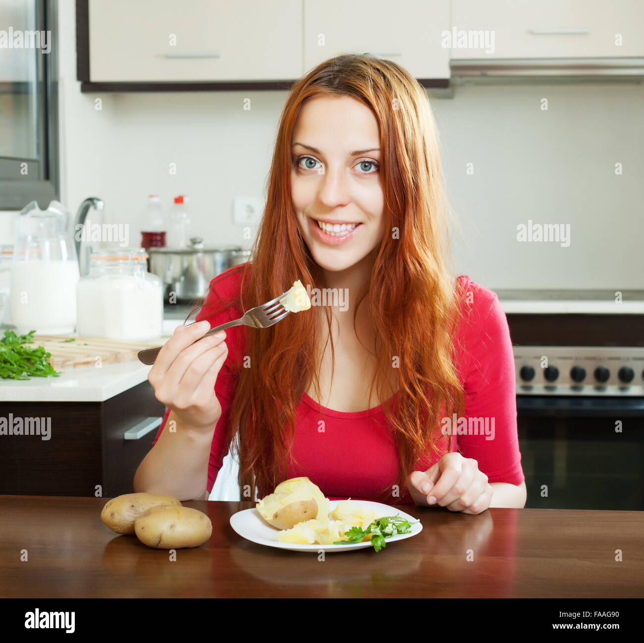 positive girl eating jacket potatoes at home interior Stock Photo - Alamy