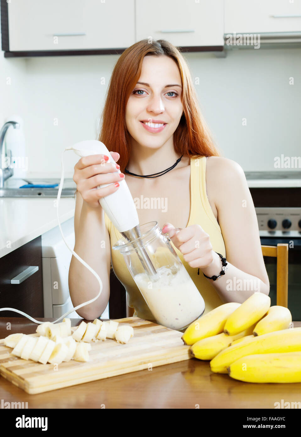 cheerful woman making milk shake with bananas at home Stock Photo - Alamy