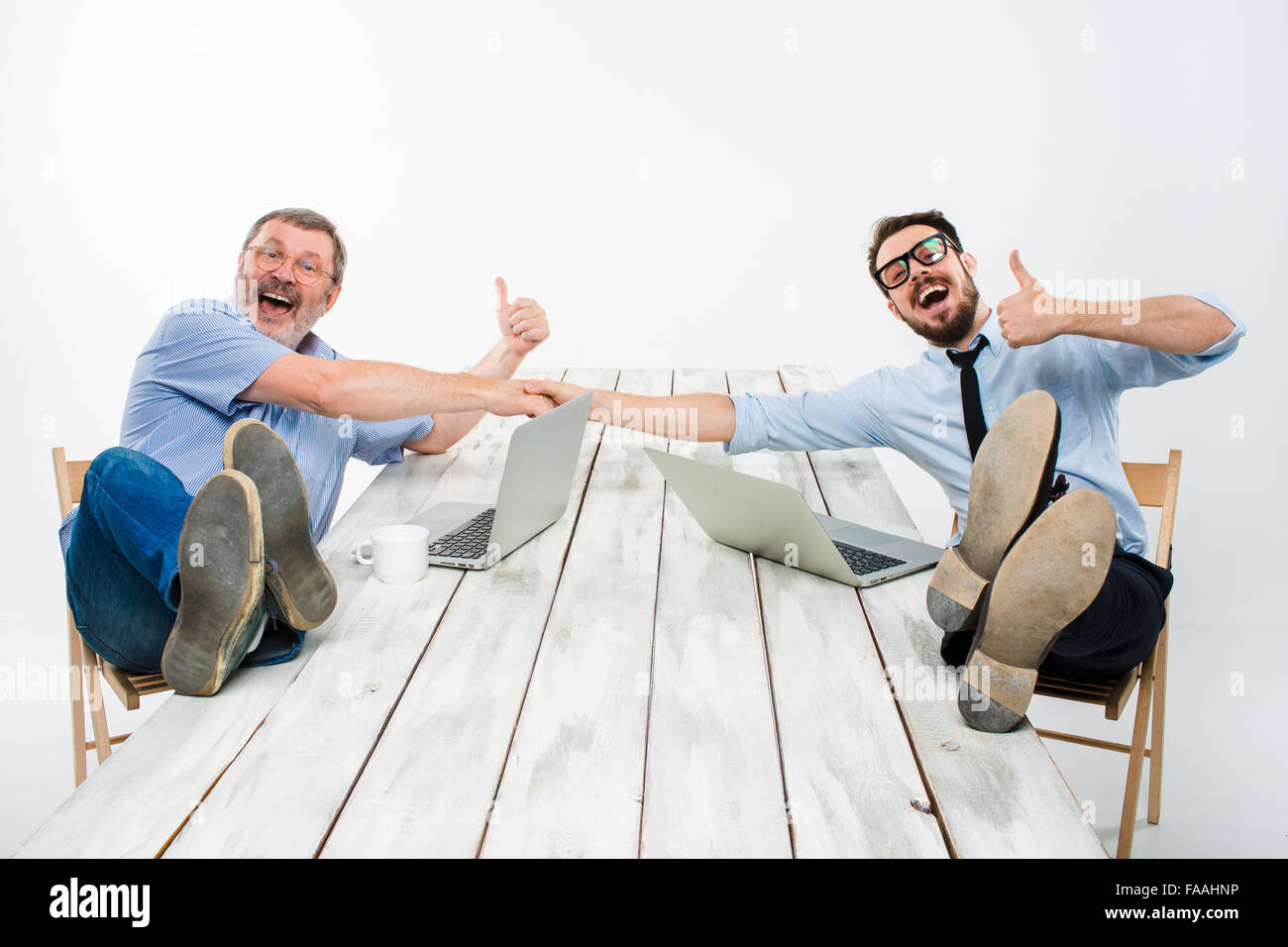 The two smiling businessmen with legs over table Stock Photo - Alamy