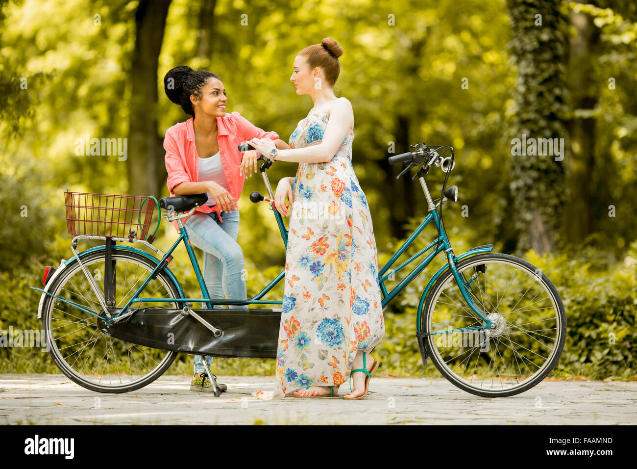 Young women posing by the bicycle Stock Photo - Alamy