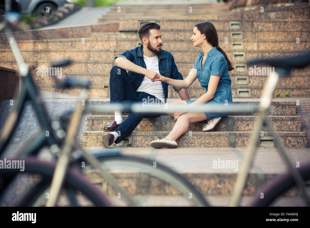 Young couple sitting opposite a bicycle Stock Photo - Alamy