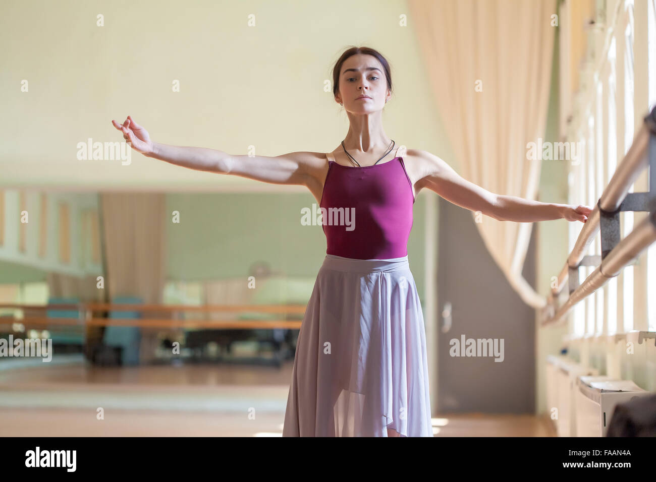 classic ballet dancer posing at barre on rehearsal room background ...