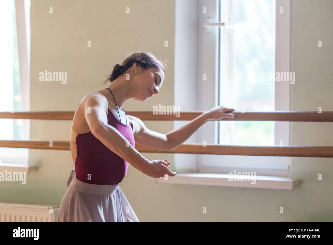 classic ballet dancer posing at barre on rehearsal room background ...