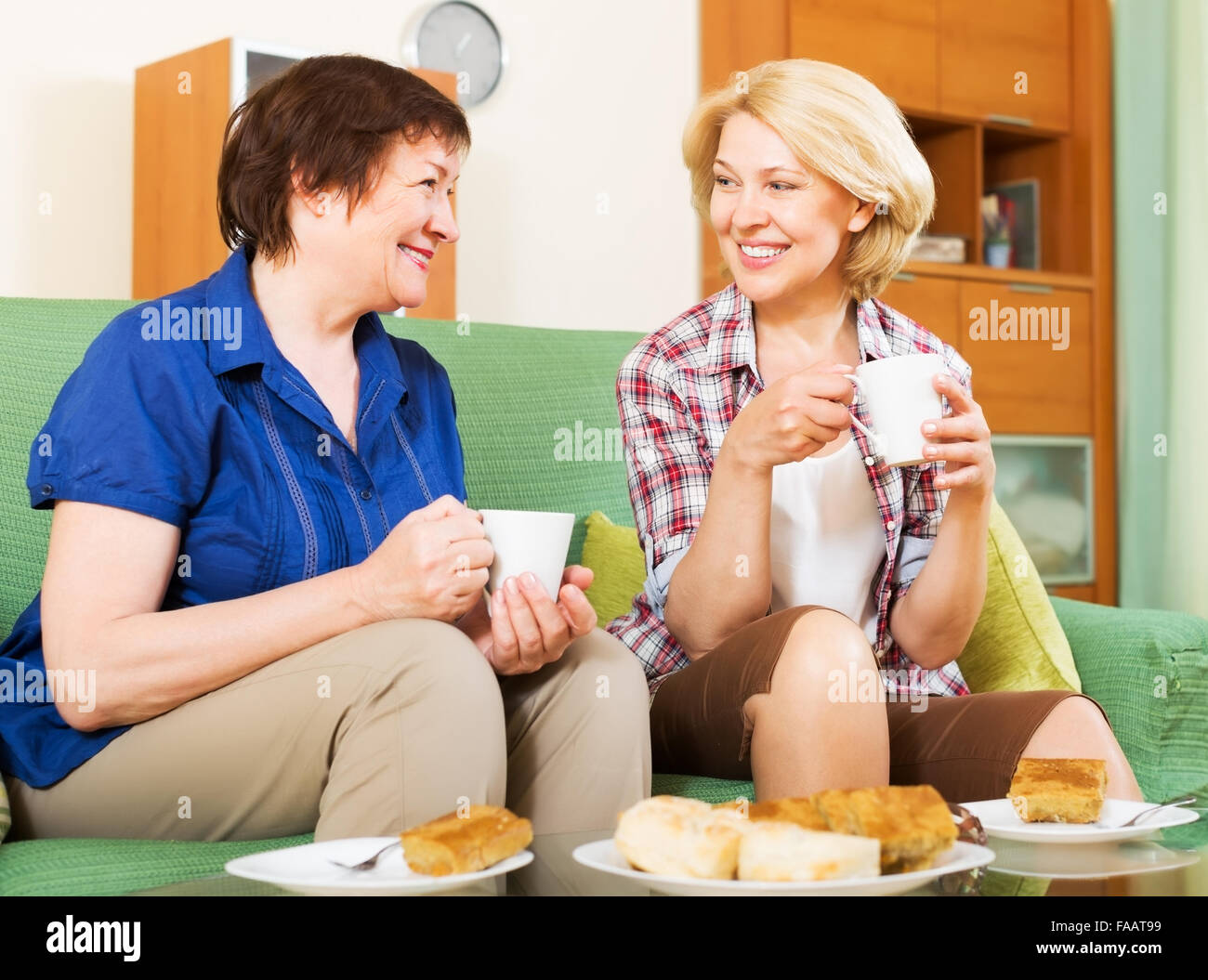 Two women colleagues in years drinking tea and talking during coffee ...