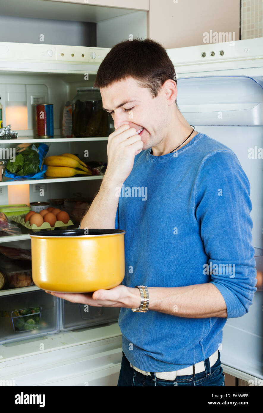 man holding her nose because of bad smell from food near refrigerator ...