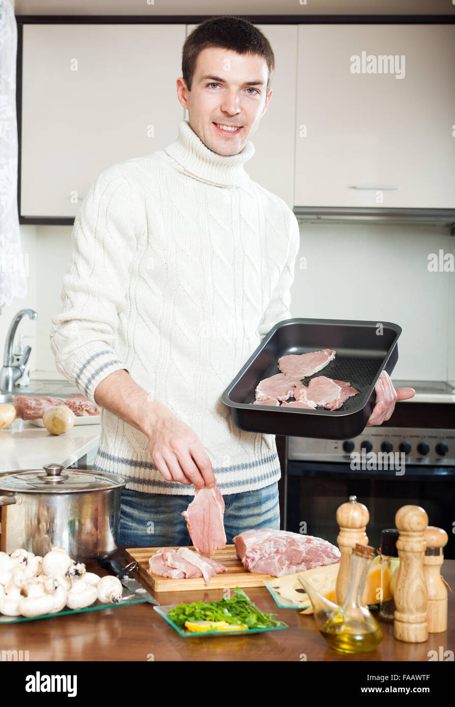 Ordinary young man cooking french-style meat at home kitchen Stock ...