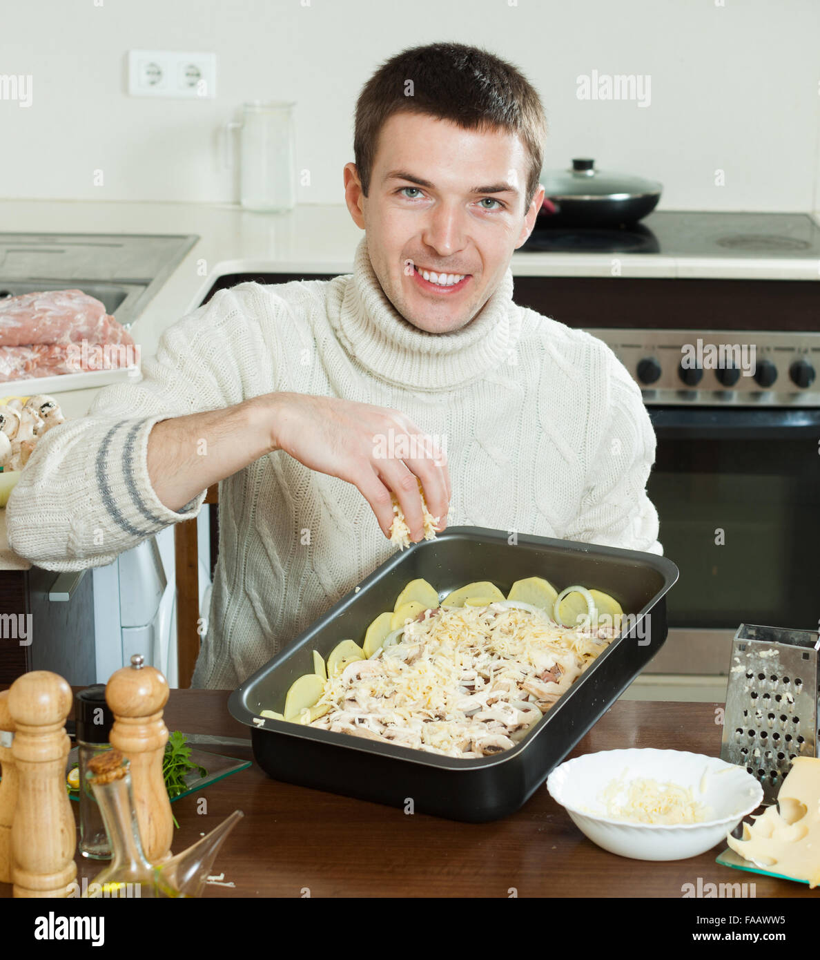 Man cooking french-style meat. Adding grated cheese in roasting pan ...