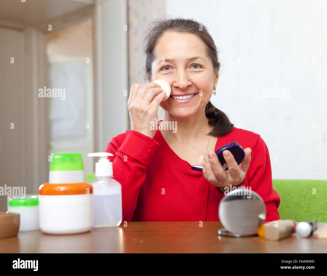 mature woman in red dress puts facepowder on her face Stock Photo - Alamy
